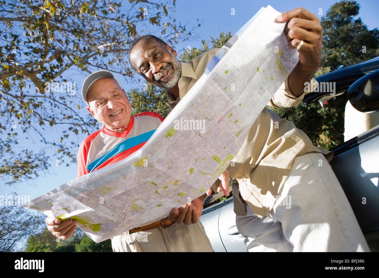 Two senior men reading map, smiling Stock Photo - Alamy
