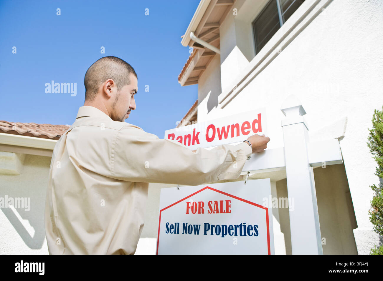 Young man putting up 'for sale notice' Stock Photo - Alamy