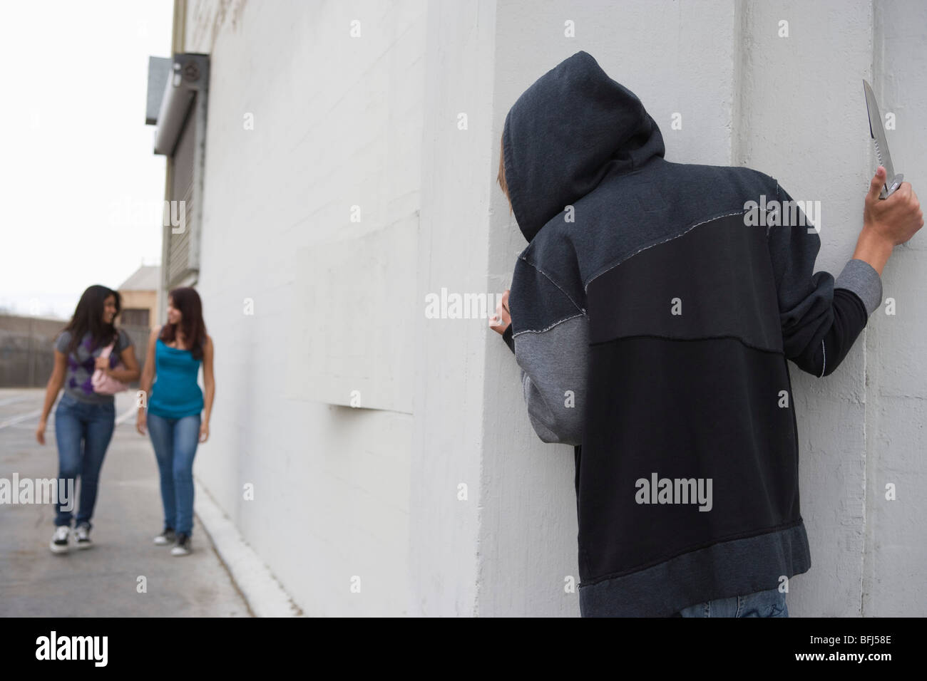 Robber with knife hiding behind corner and waiting for two girls Stock ...