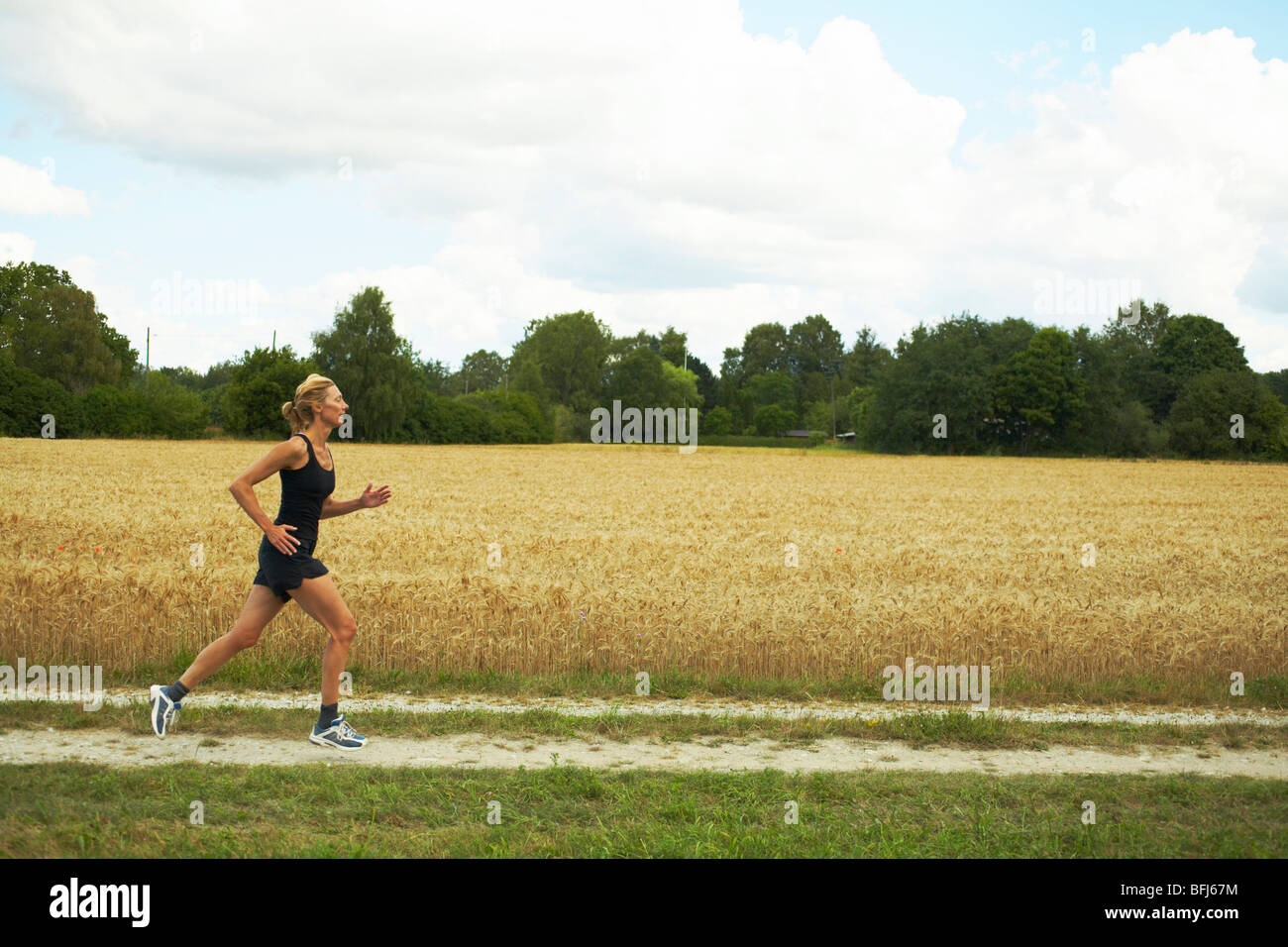 Woman jogging in an open landscape, Sweden Stock Photo - Alamy