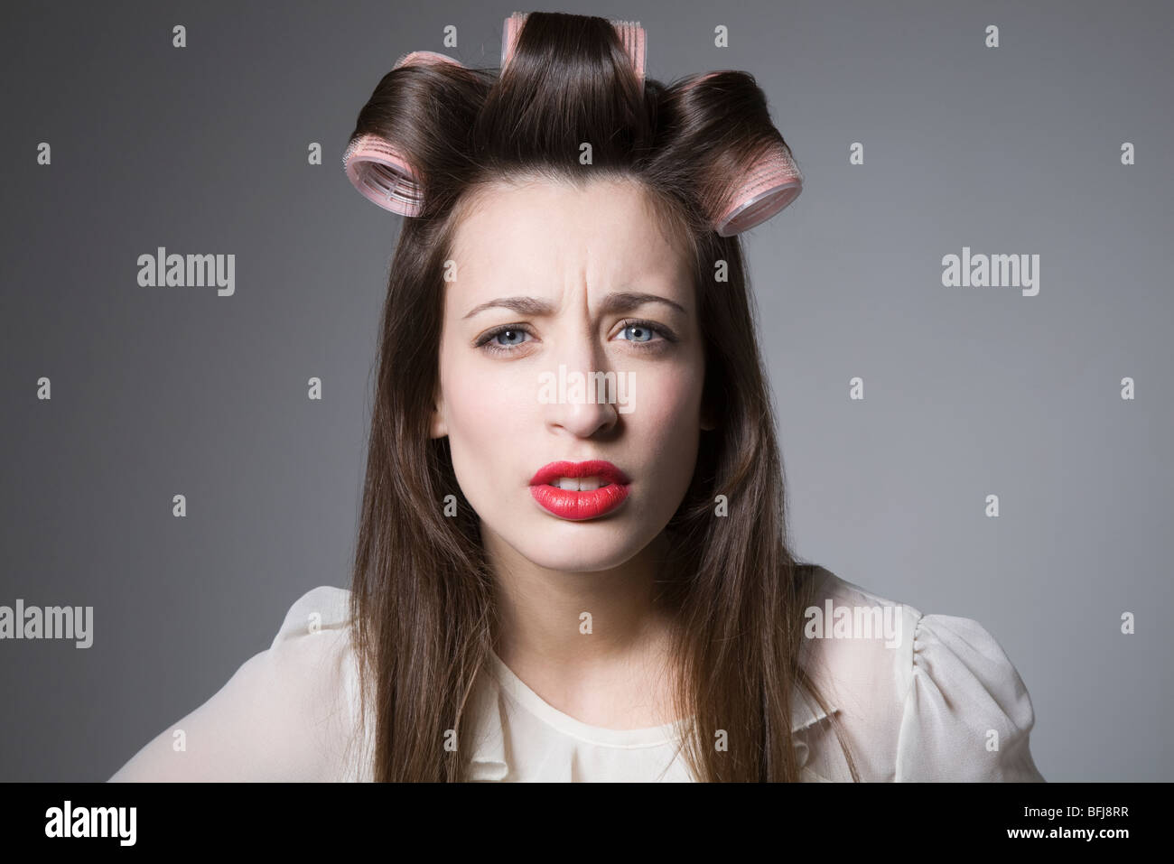 Scowling young woman with hair curlers and red lipstick Stock Photo - Alamy