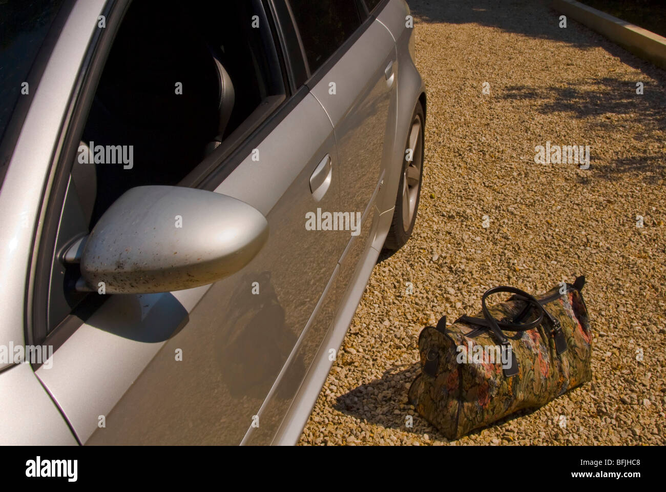 Side of a silver car with hold all travel bag on the ground Stock Photo ...