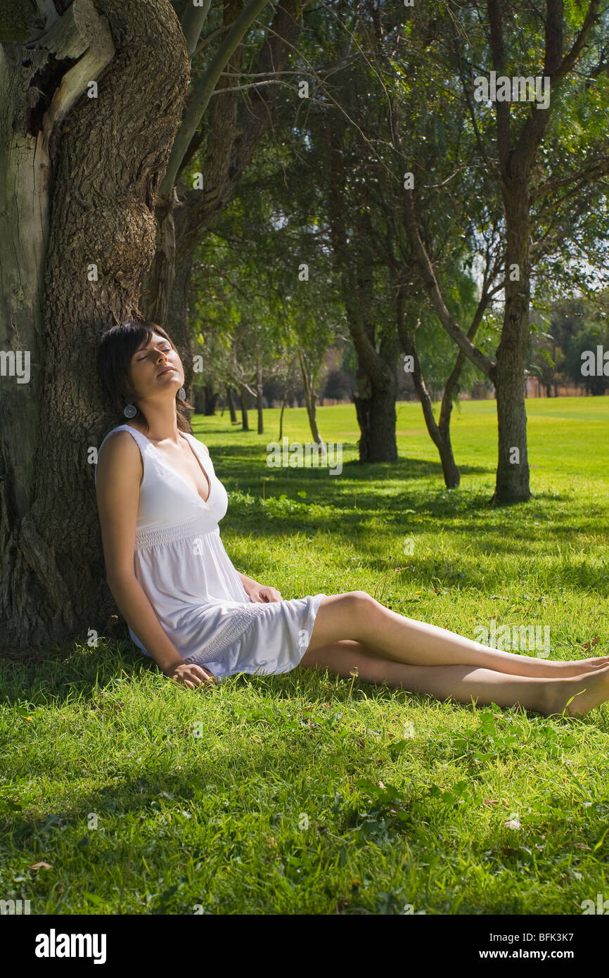 Hispanic woman relaxing against tree in park Stock Photo - Alamy