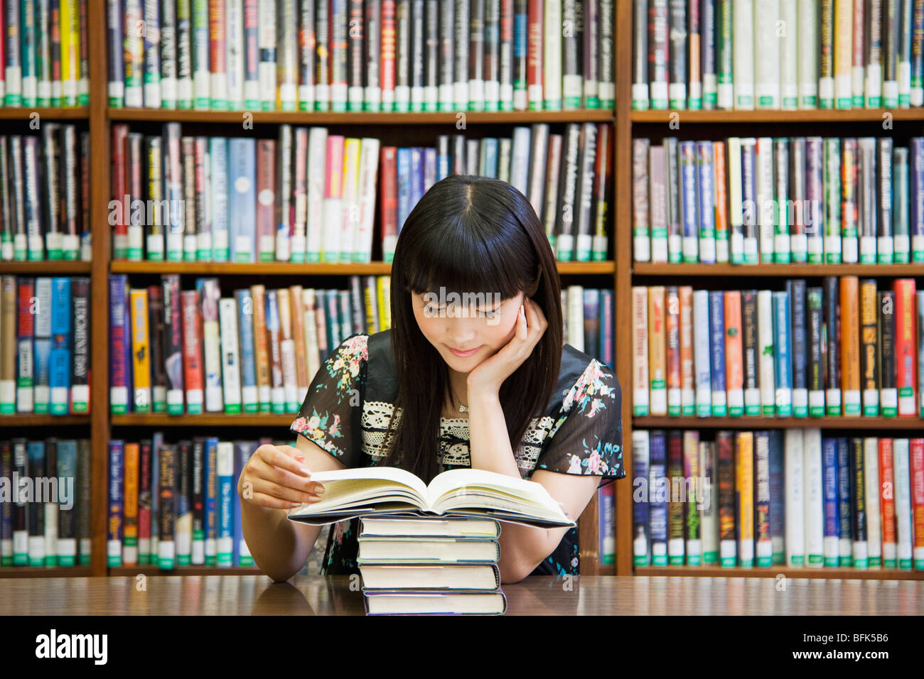 Asian woman reading book in library Stock Photo - Alamy