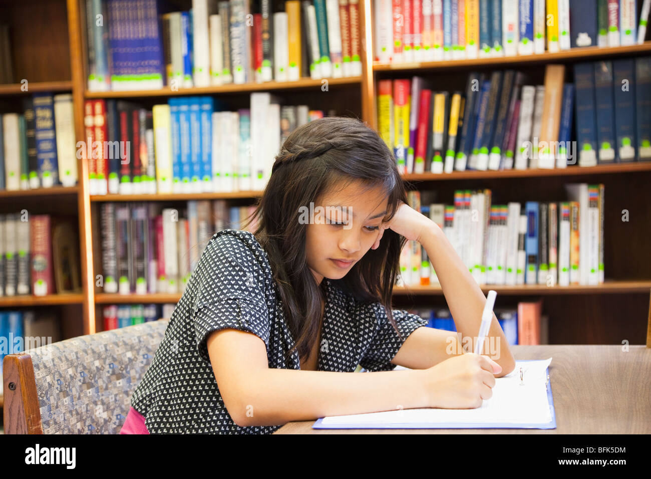Asian girl doing homework in library Stock Photo - Alamy