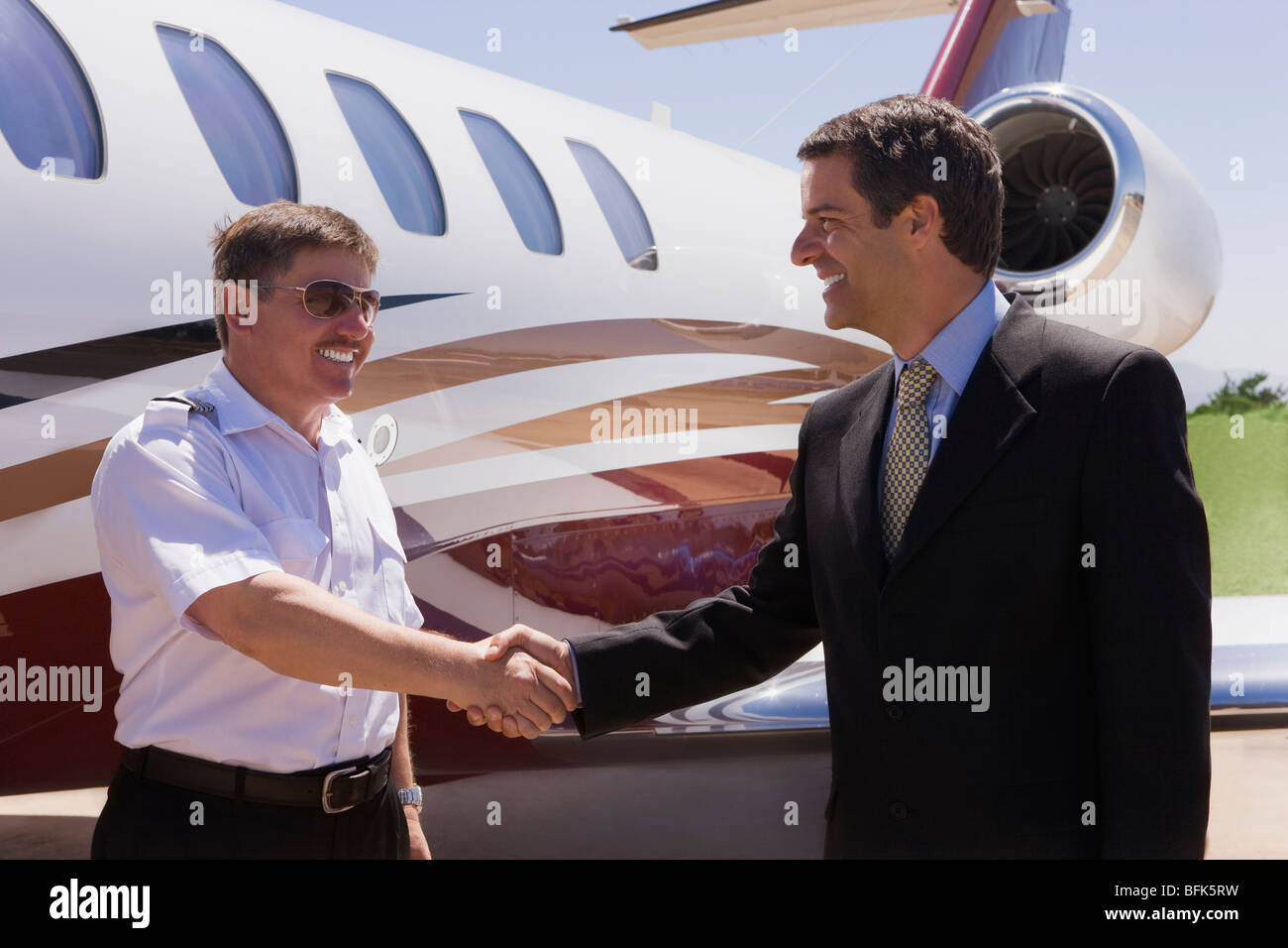 Businessman and pilot shaking hands outside private jet Stock Photo - Alamy