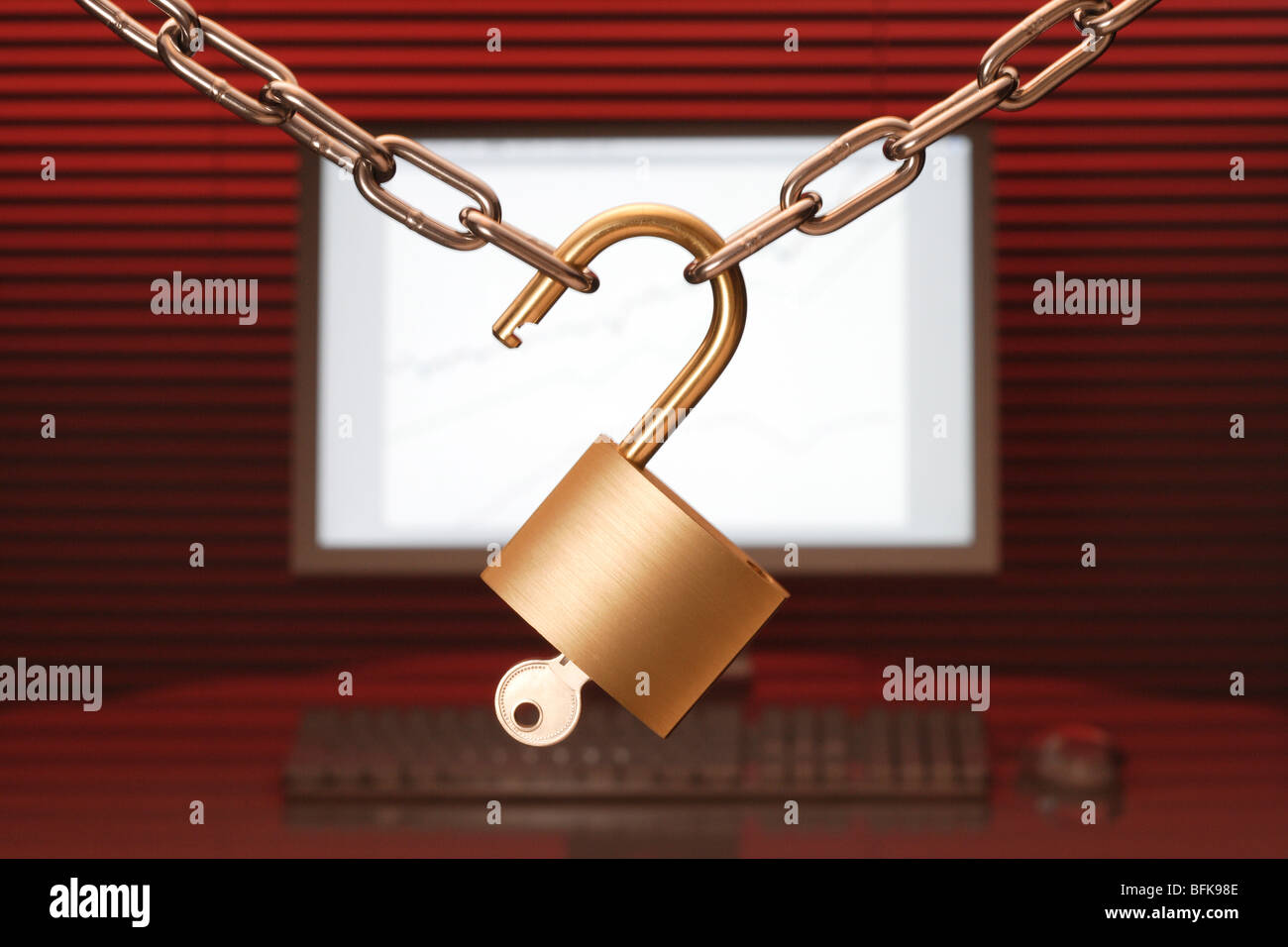 Chain and padlock with key computer in background Stock Photo - Alamy