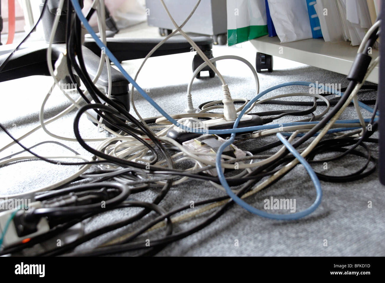 Tangled cables under desk Stock Photo - Alamy