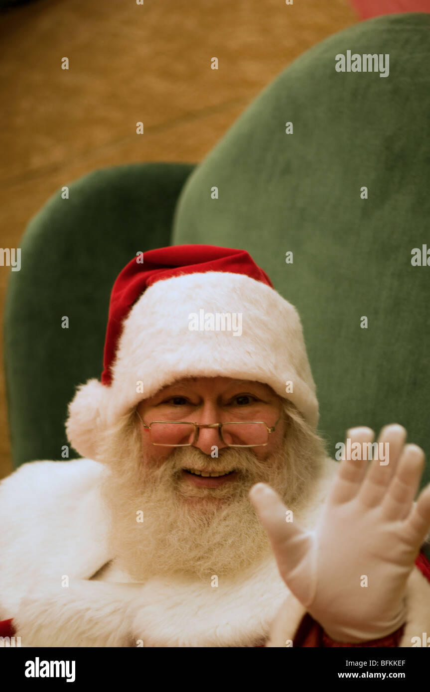 Santa sitting in large green chair waving Stock Photo - Alamy