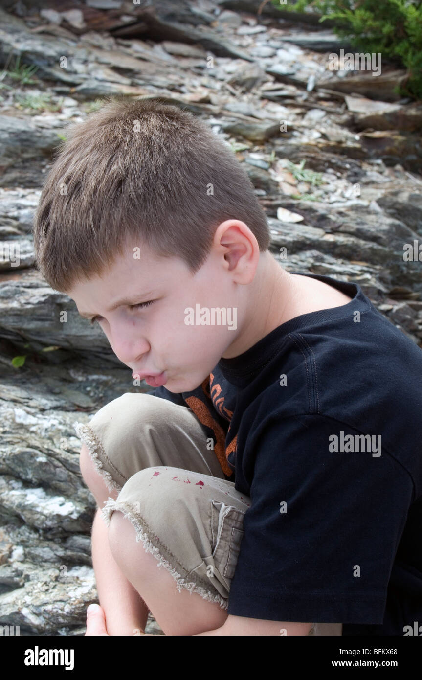 Young boy sitting crouched on rock at Beaver tail light house staring ...