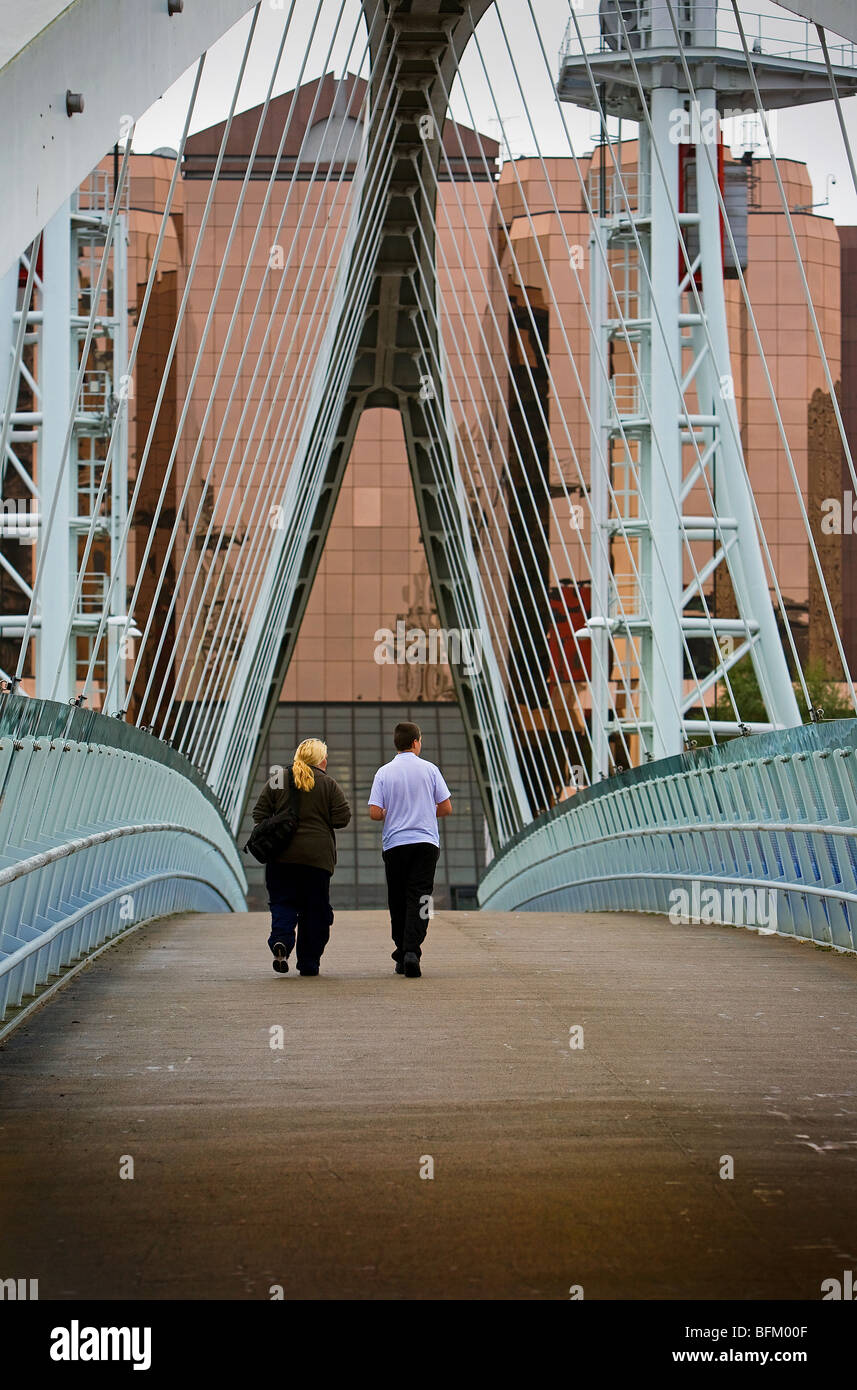 Two people walking across The Millennium Bridge from The Lowry side at ...