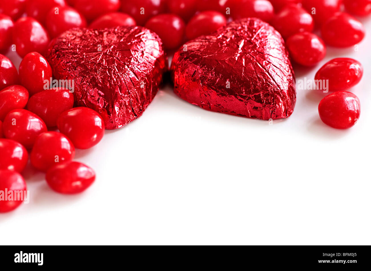 Red Valentine's candies and foil wrapped chocolates on white background ...