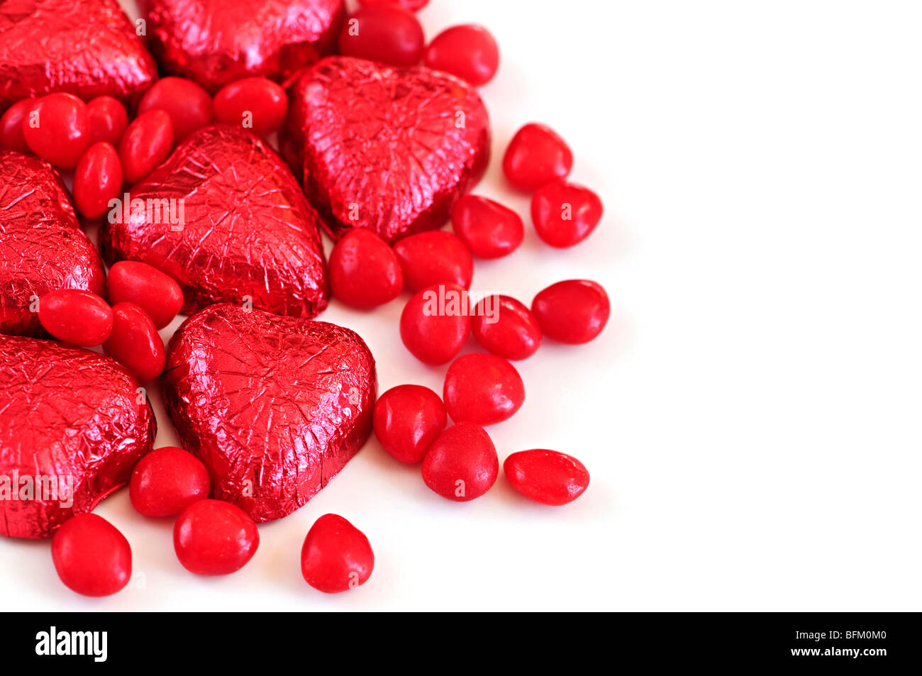Red Valentine's candies and foil wrapped chocolates on white background ...
