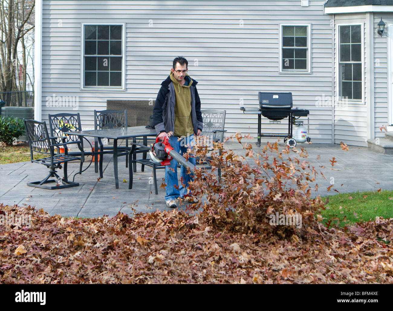 A homeowner man blowing leaves. A typical autumn scene in urban America ...