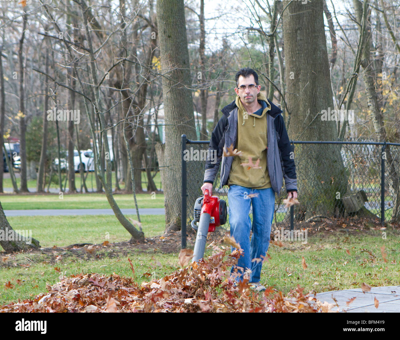 A homeowner man blowing leaves. A typical autumn scene in urban America ...