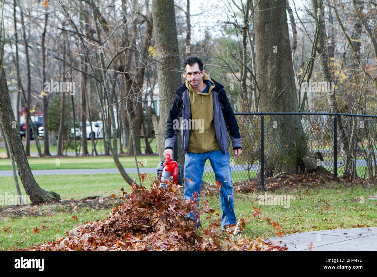 A homeowner man blowing leaves. A typical autumn scene in urban America ...