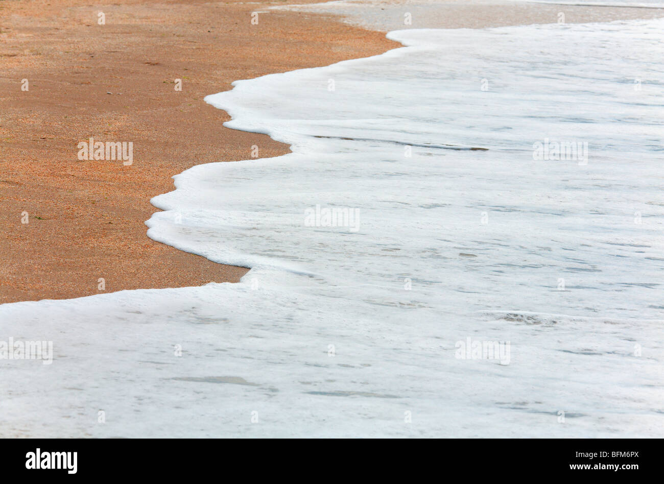 Sea surf foam on coastline sand Stock Photo - Alamy