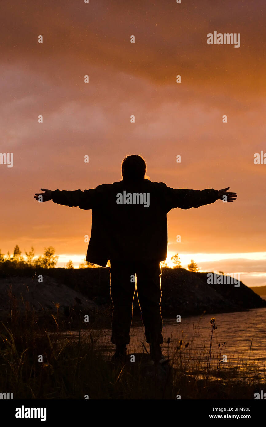 man stands back, stretching hands in sides, and looks at sunset Stock ...