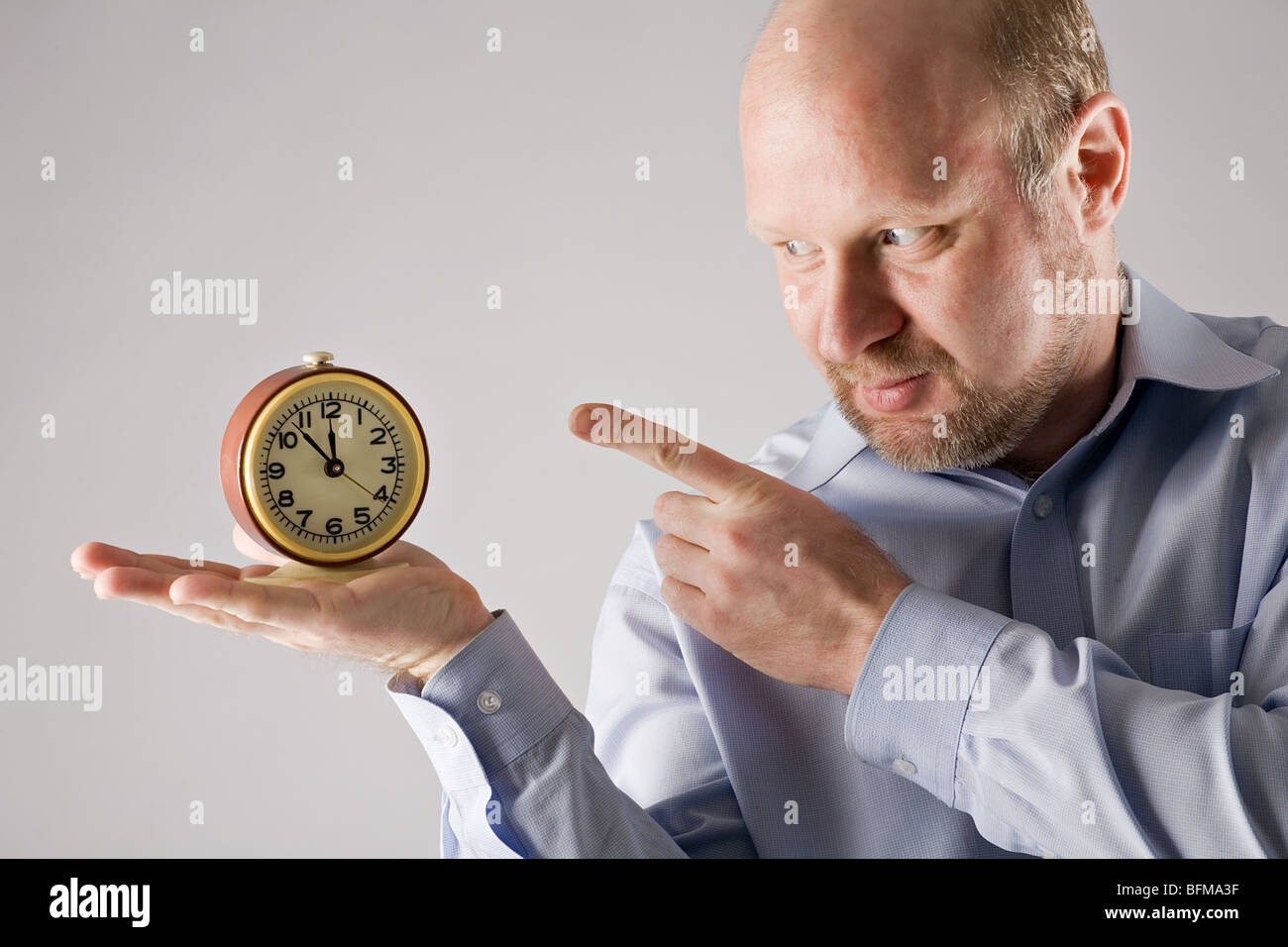 man shows at clock standing on his hand, isolated on grey Stock Photo ...