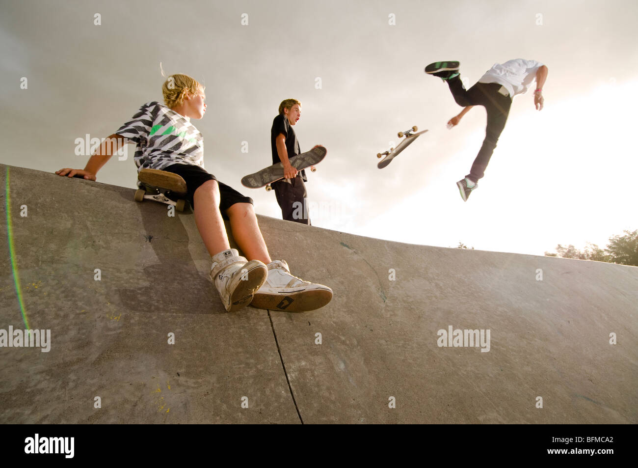 3 boys doing tricks in skate park with setting sun, Cambridge, New ...