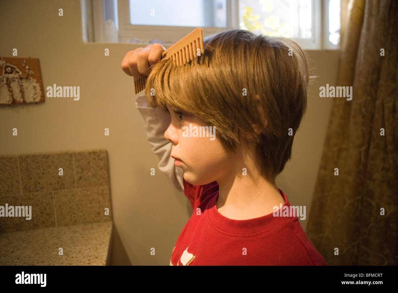 seven year old boy combing his hair in the bathroom before school Stock ...