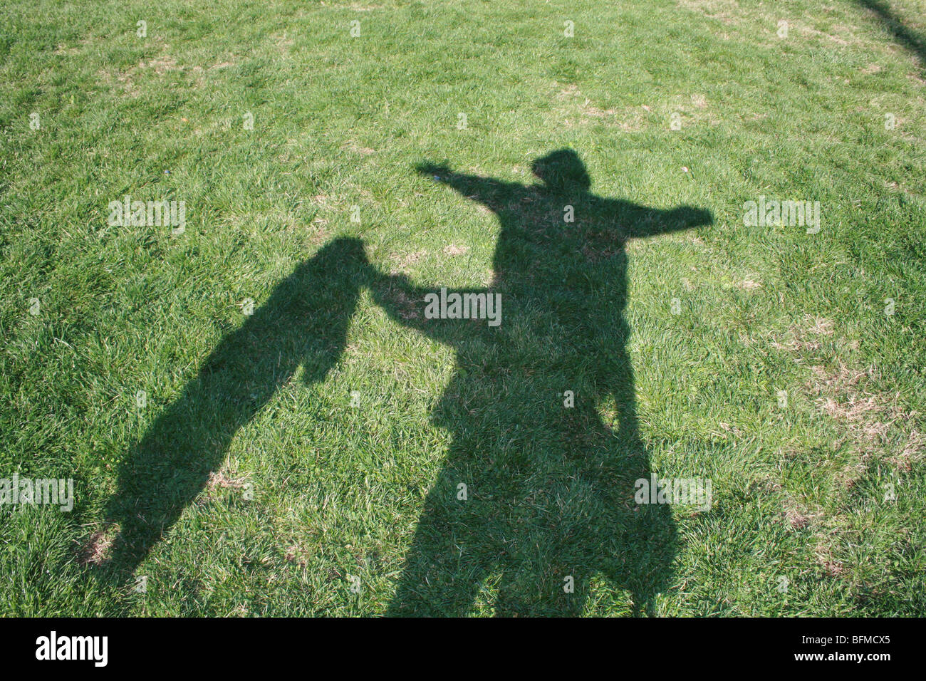 shadow of a mother carrying her child on her shoulders with raised ...