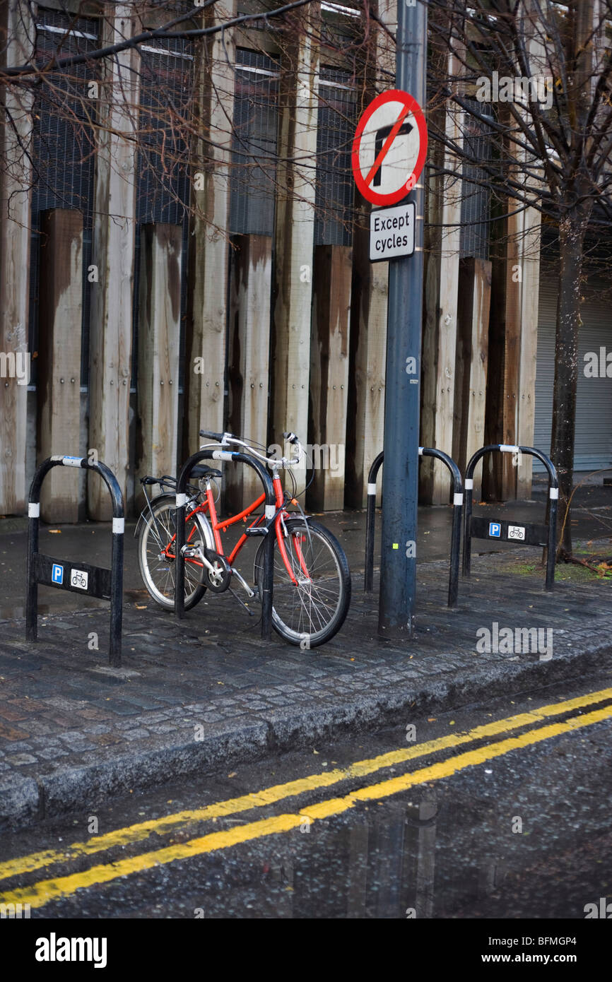 A parked push bike is secured to a street bike rack under a cycle sign ...