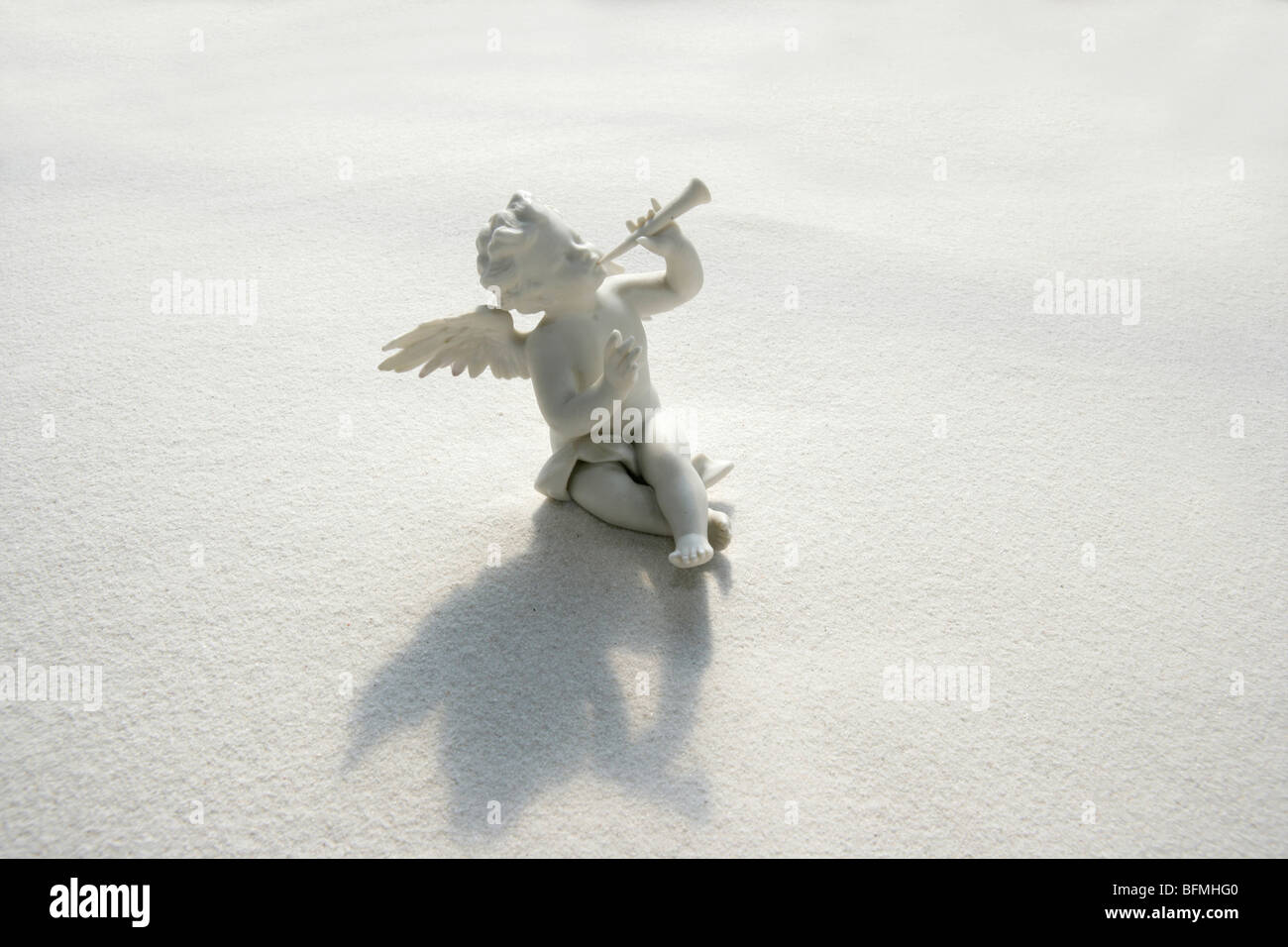 Angel figurine with musical instruments on white sand Stock Photo - Alamy