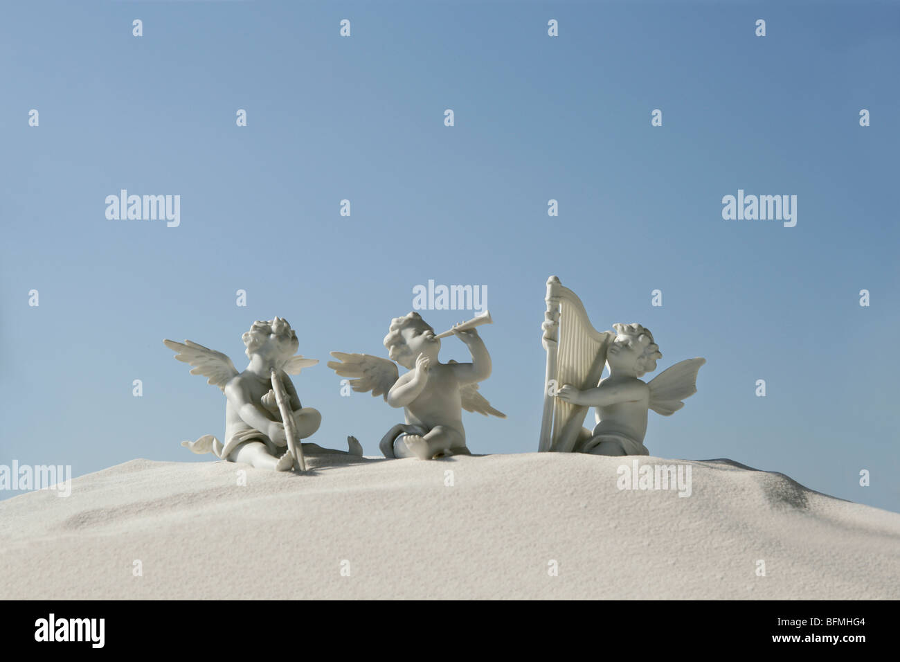 Angel figurines with musical instruments on white sand Stock Photo - Alamy