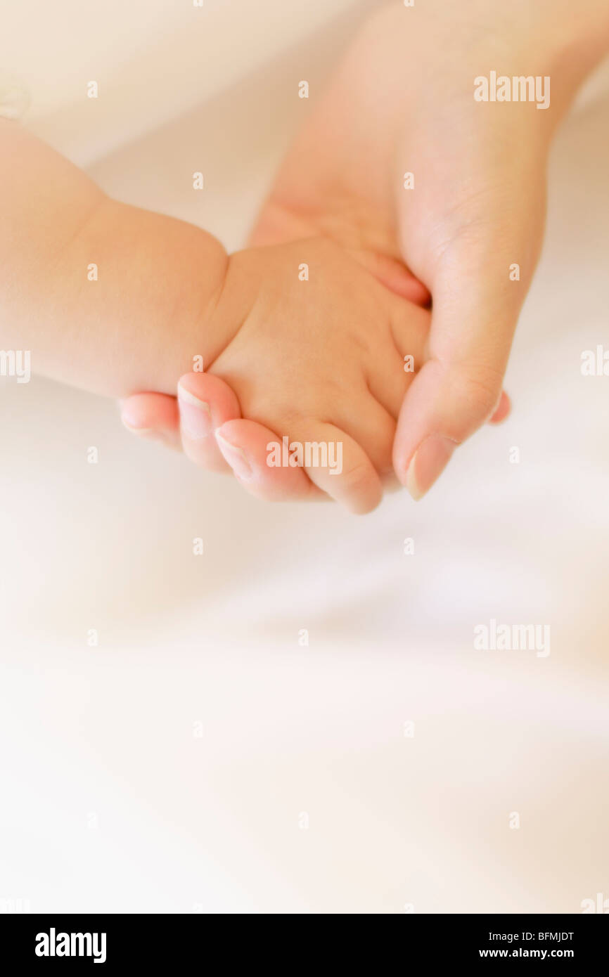 Mother and baby holding hands Stock Photo - Alamy