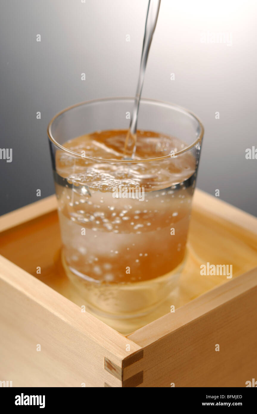 Sake pouring into glass, colored background Stock Photo - Alamy