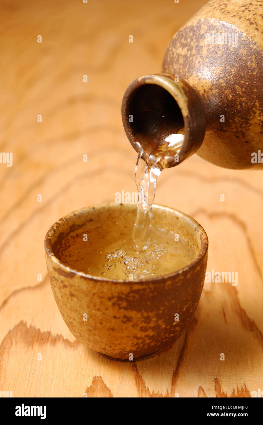 Sake pouring into Sake cup, close up Stock Photo - Alamy