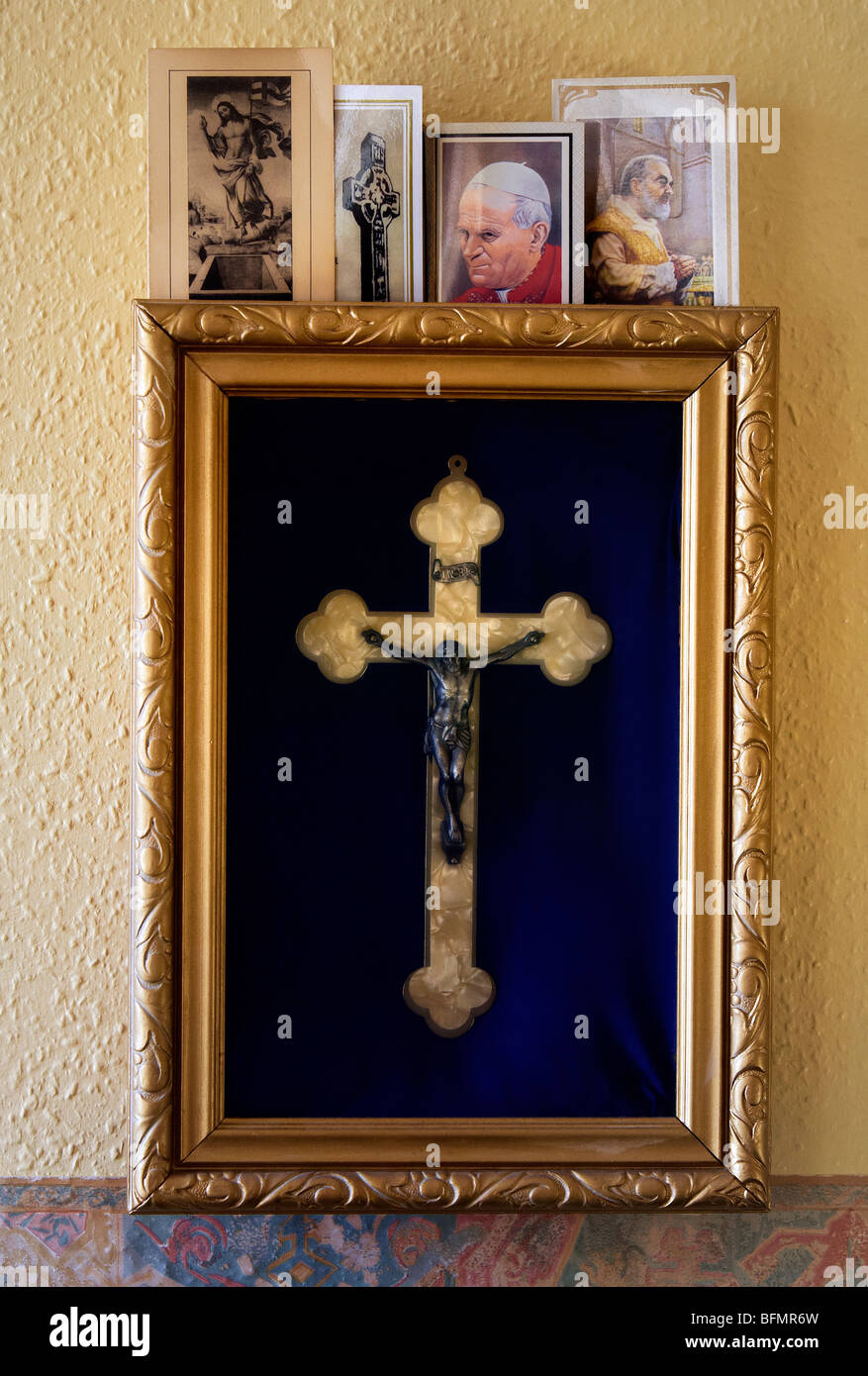 A crucifix and religious cards are photographed on a wall in a house in ...