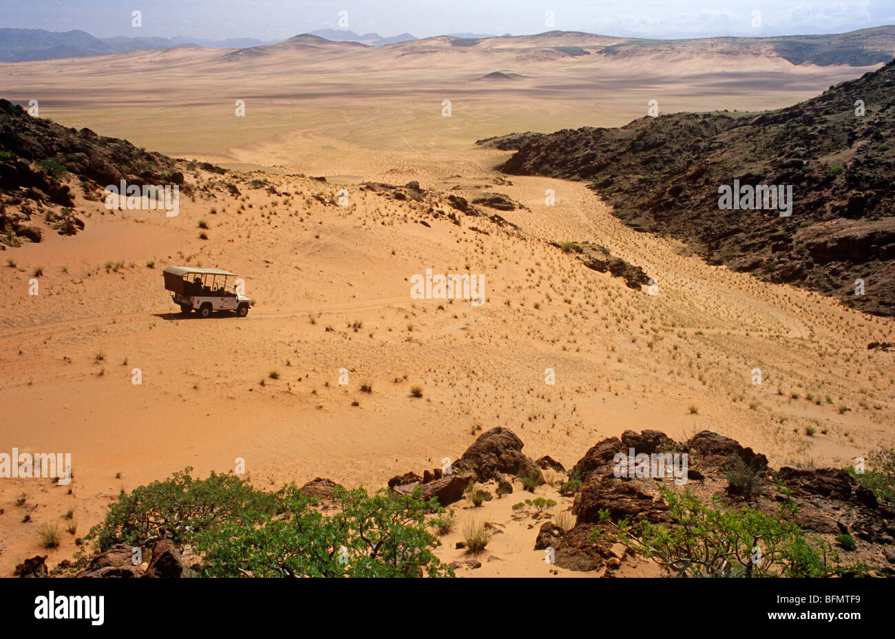 Namibia, Kaokoveld, Kaokoland. A tourist safari vehicle heads down ...