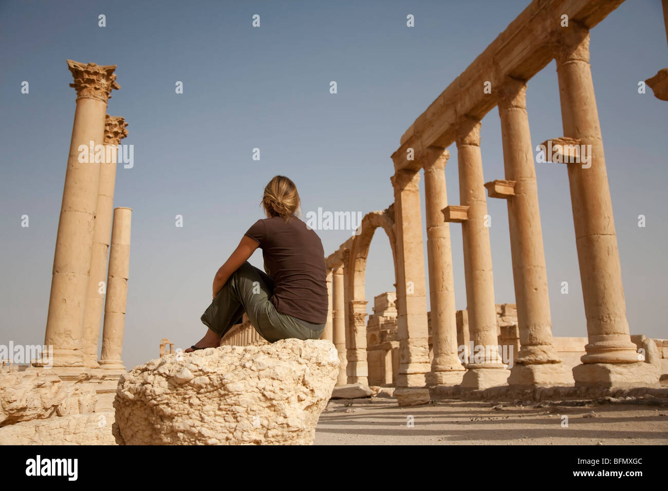 Syria, Palmyra. A tourist sits amongst the ancient ruins of Queen ...