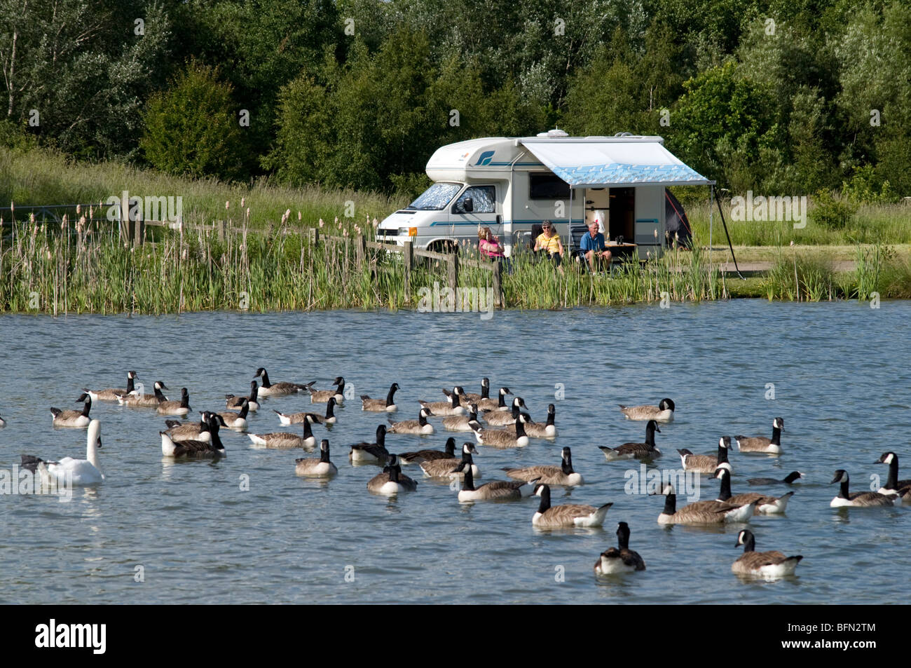 People relaxing with Camper van parked at the lakeside of Rother Valley ...