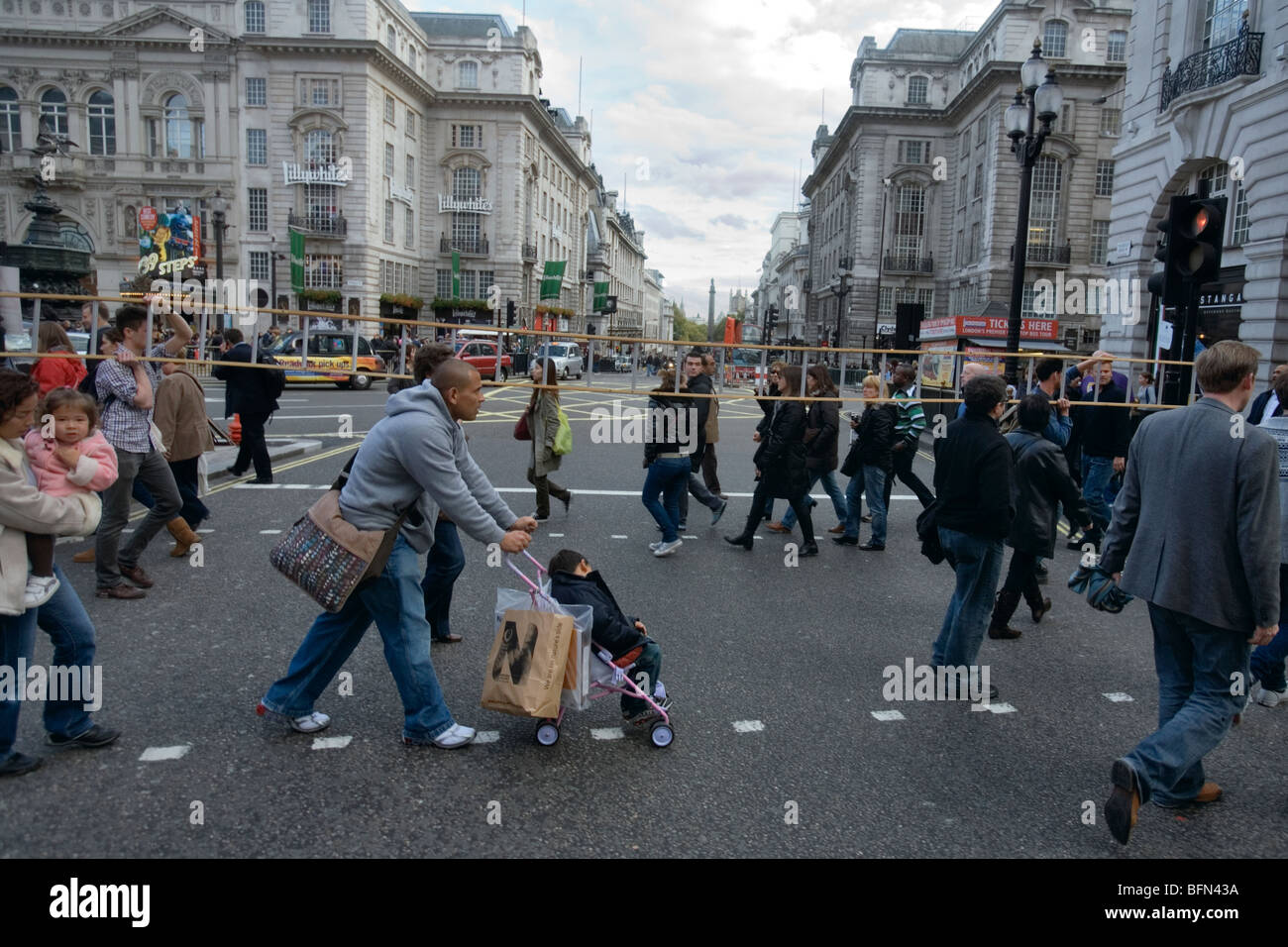 a man with a long ladder crosses the street at piccadilly circus in ...