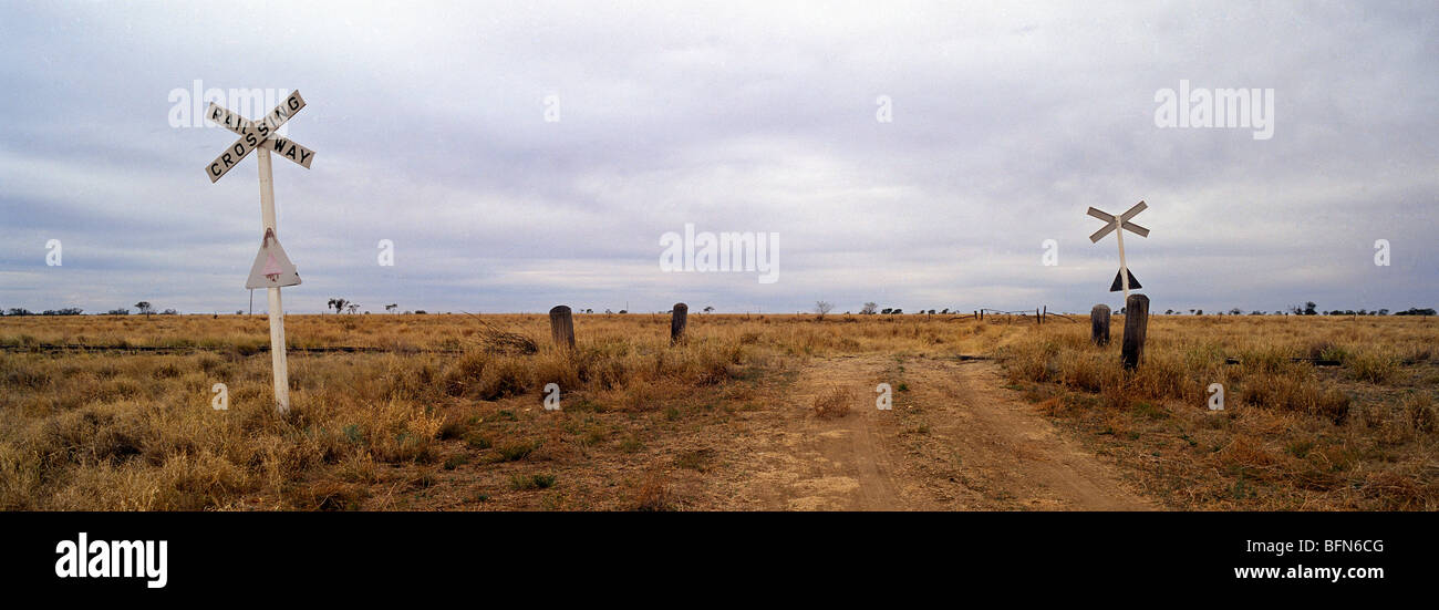 A track crosses a remote outback railway line on a featureless plain ...