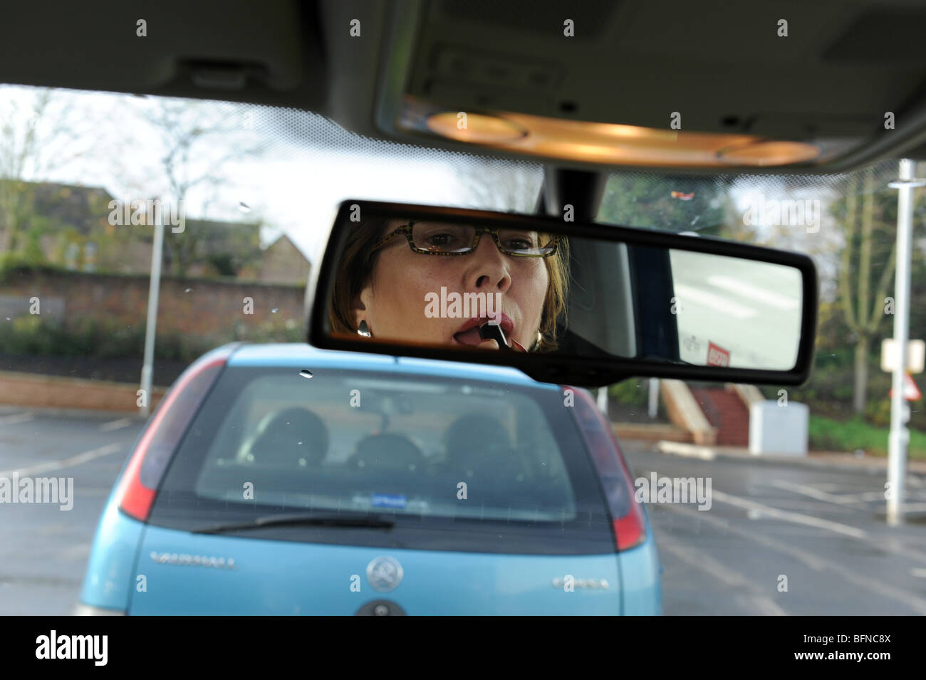 Female woman driver applying lipstick at the wheel of car uk Stock ...