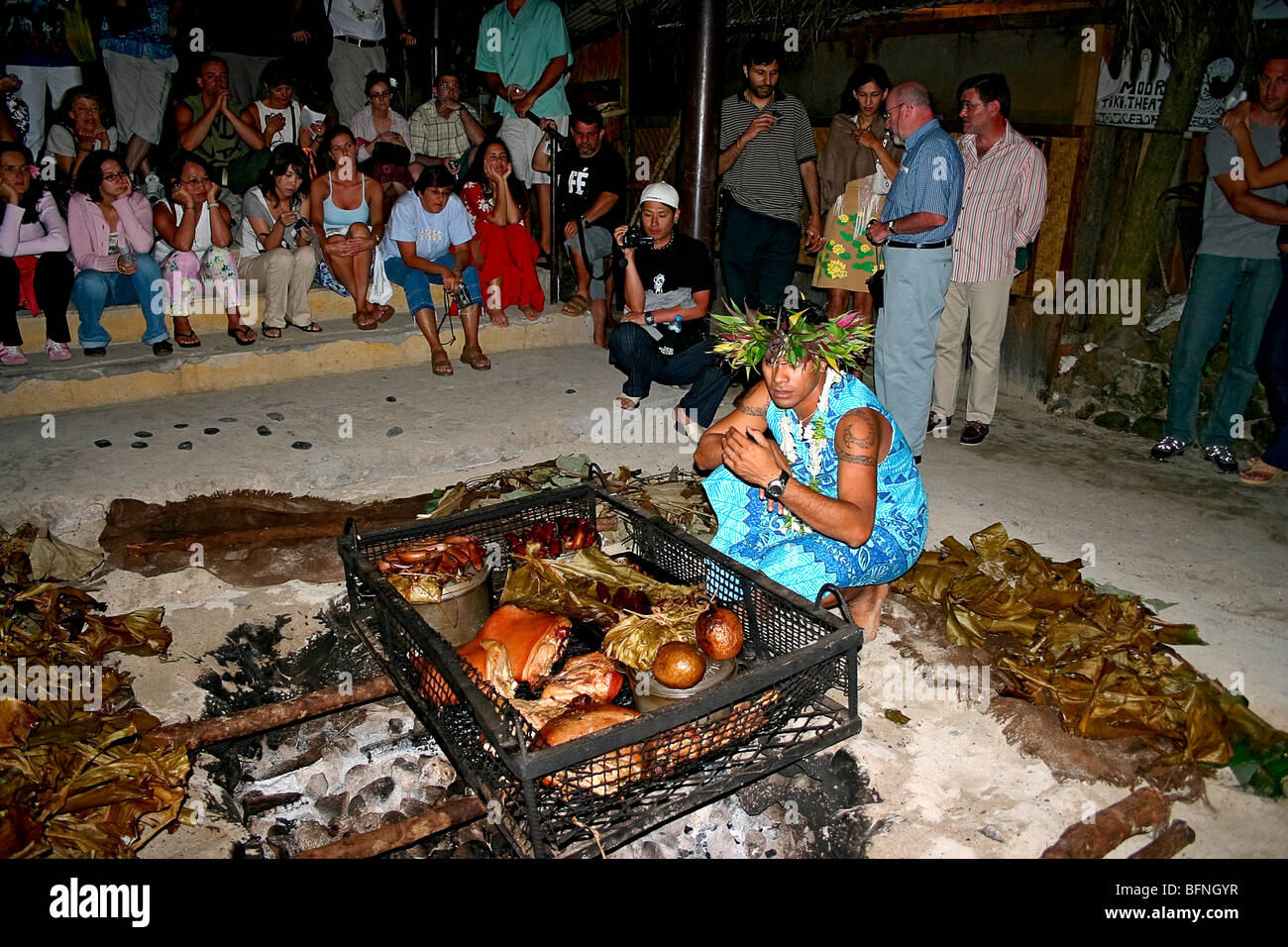 Man prepares food baked in pit, traditional Tahitian stye, Tiki Village ...