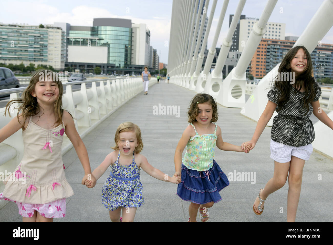 Four little girl group walking in the city bridge downtown buildings ...