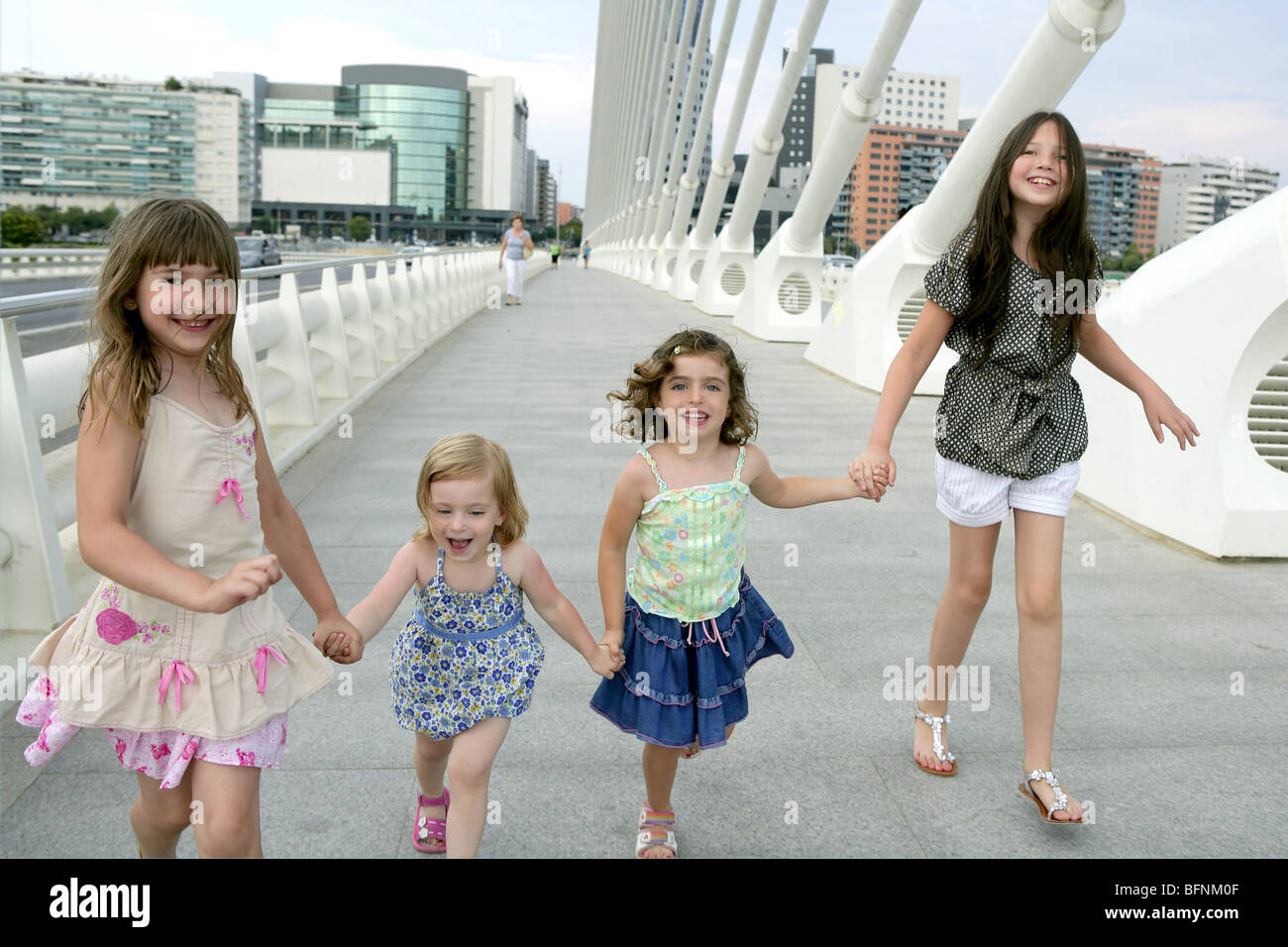Four little girl group walking in the city bridge downtown buildings ...