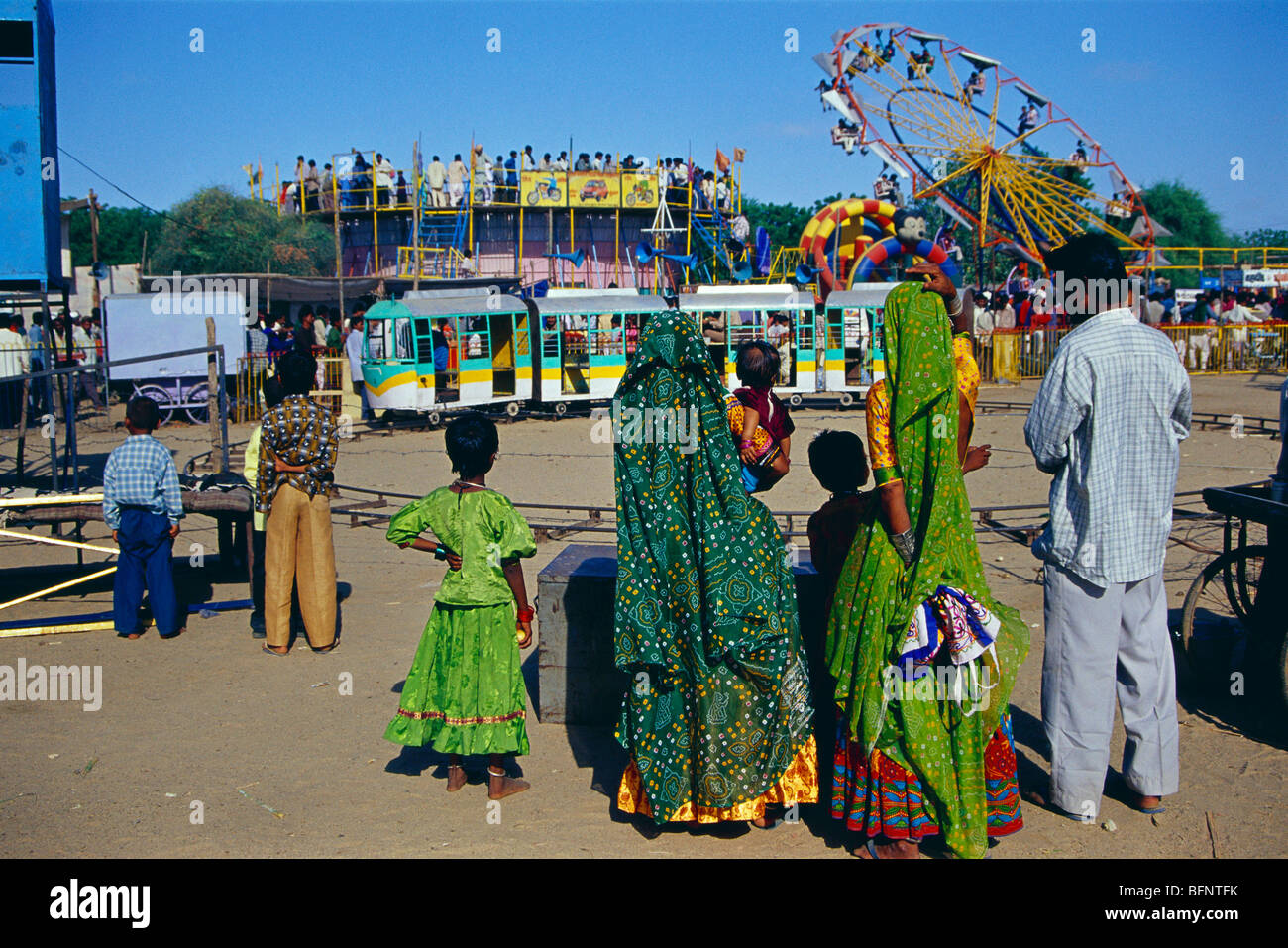 Rural family watching train ride and ferris wheel ; Ravechi fair ...