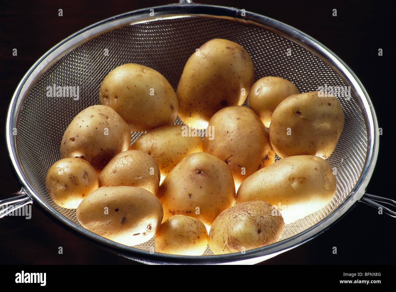 potato vegetable in steel jali on black background Stock Photo - Alamy