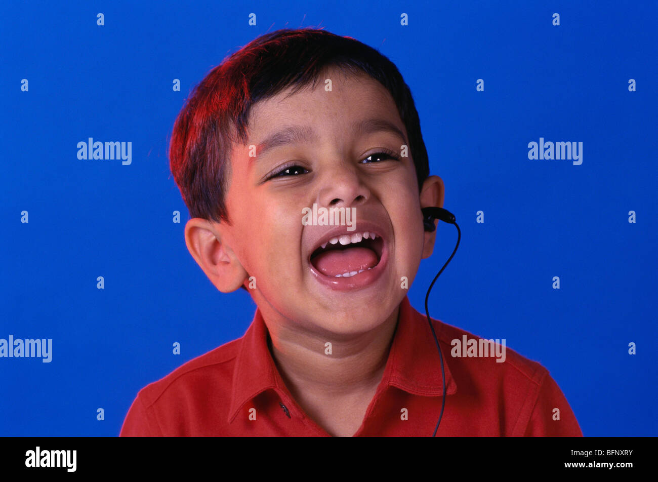 Indian boy child singing and listening to music using headphone ; India ...