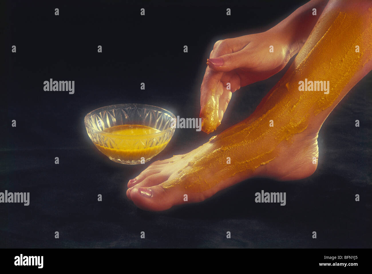Woman applying turmeric paste on foot Stock Photo - Alamy