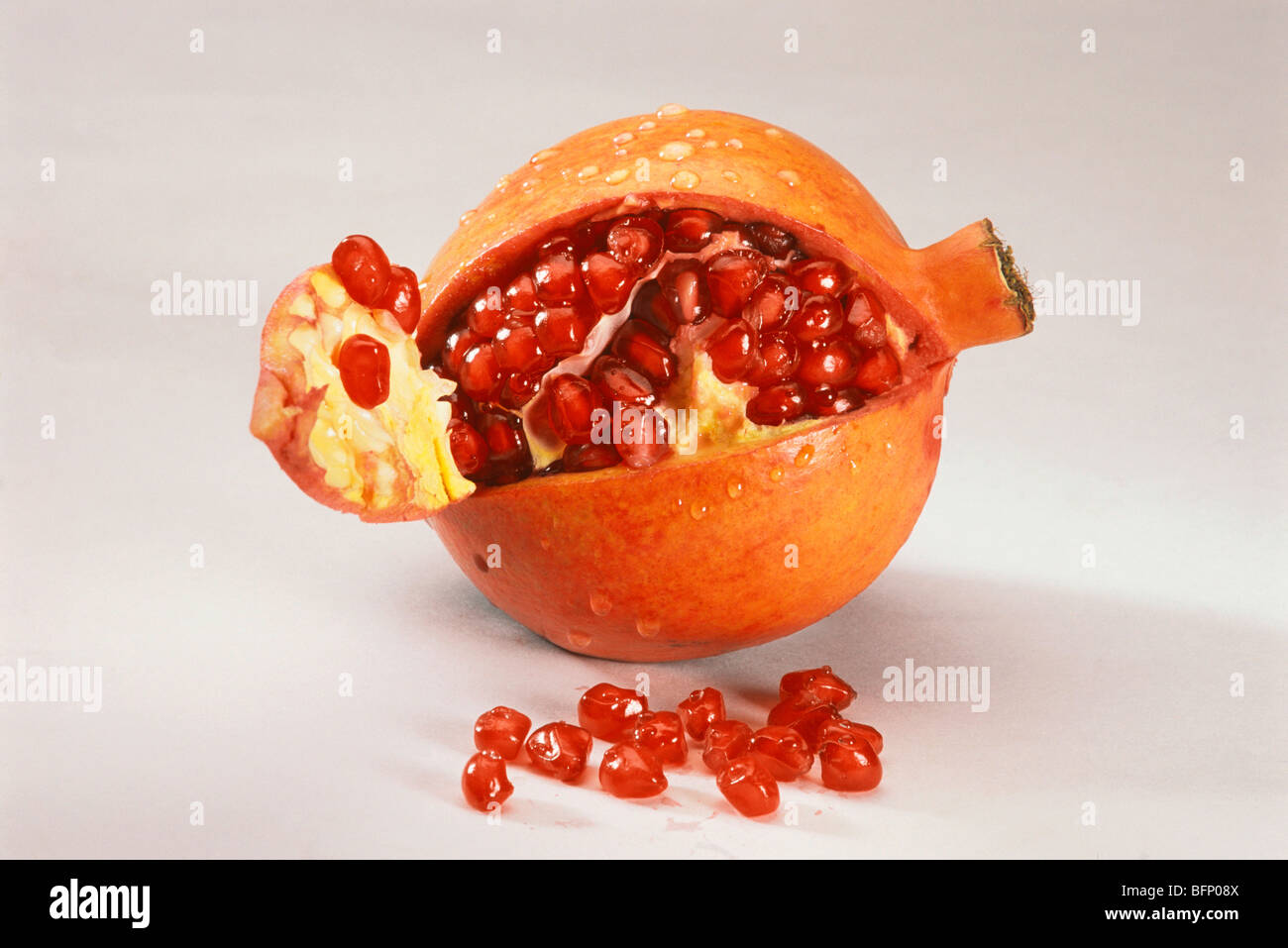 pomegranate fruit opened red seeds white background Stock Photo - Alamy