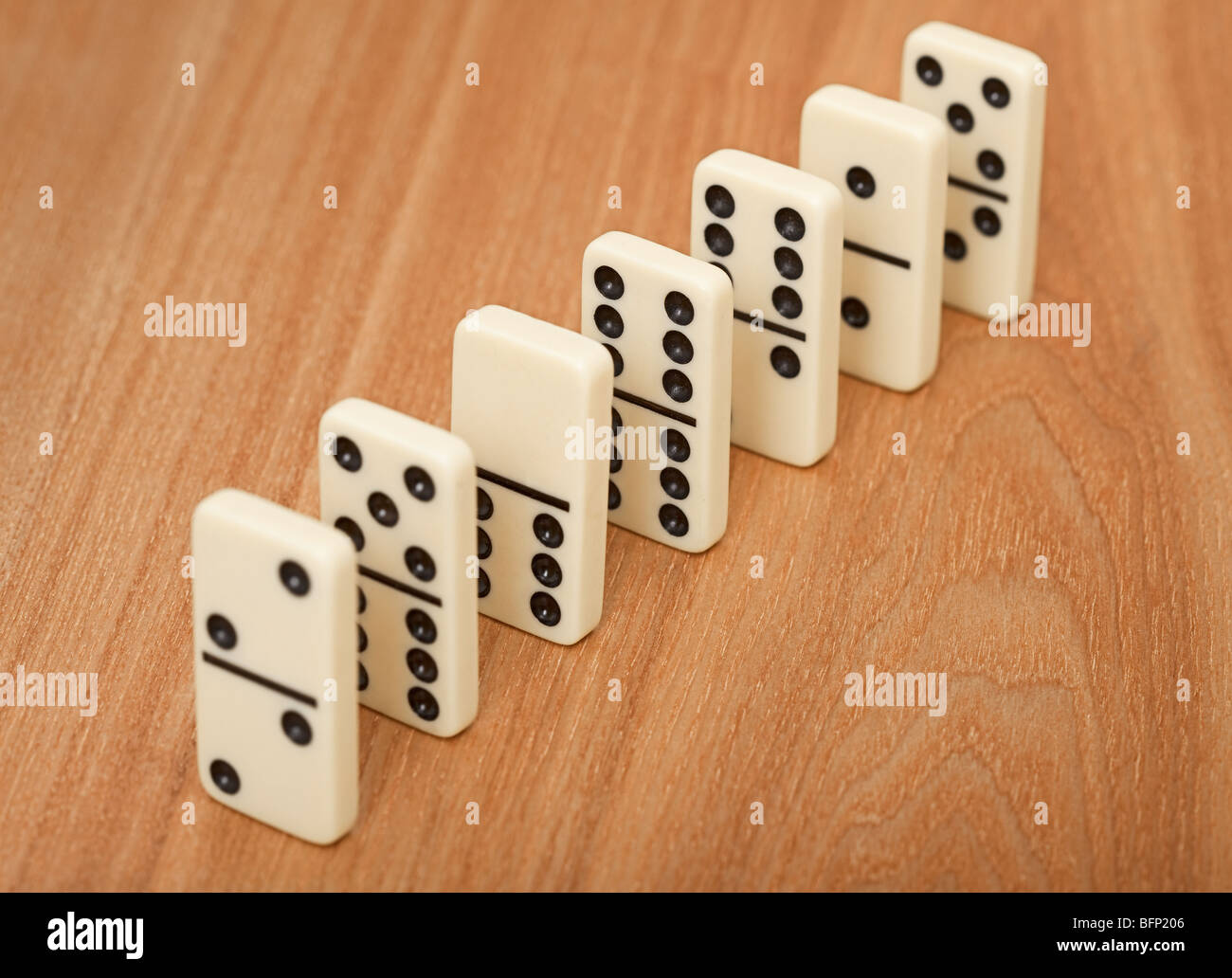 A line from seven dominoes on a wooden surface Stock Photo - Alamy