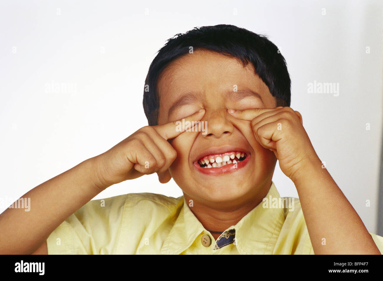 Indian boy child rubbing both eyes with fingers, keeping fingers on ...