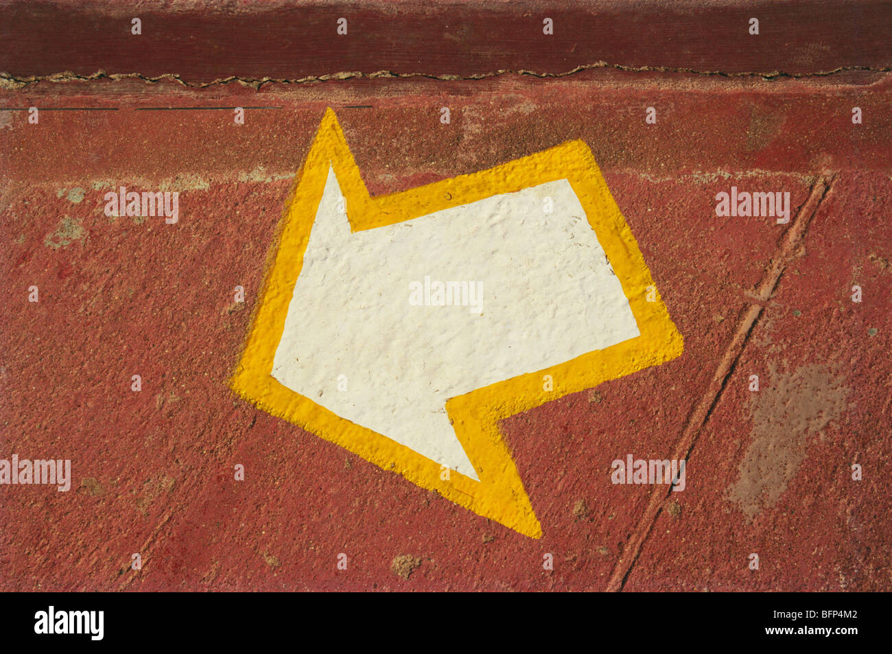 Arrow painted on the floor ; white arrow with yellow border ; sign ...